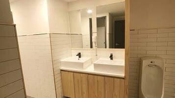 Uma casa de banho moderna com duas lavatórios, um espelho e um sanitário.