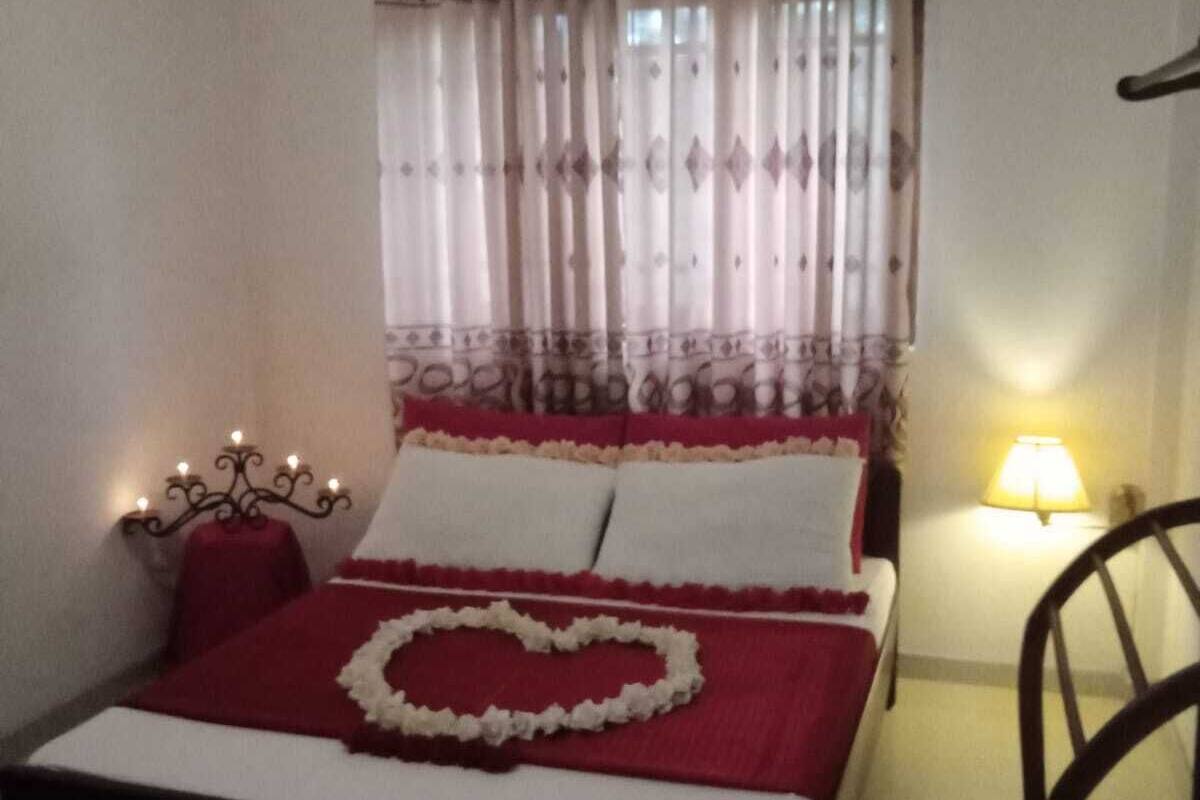 Uma cama com uma decoração em formato de coração, um abajur e uma cadeira.