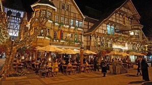 Um edifício tradicional em estilo europeu, com mesas ao ar livre e bandeiras.