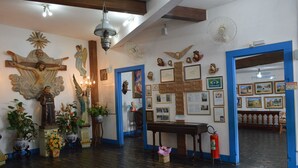 Um quarto com piso de madeira, um lustre e uma cruz na parede.