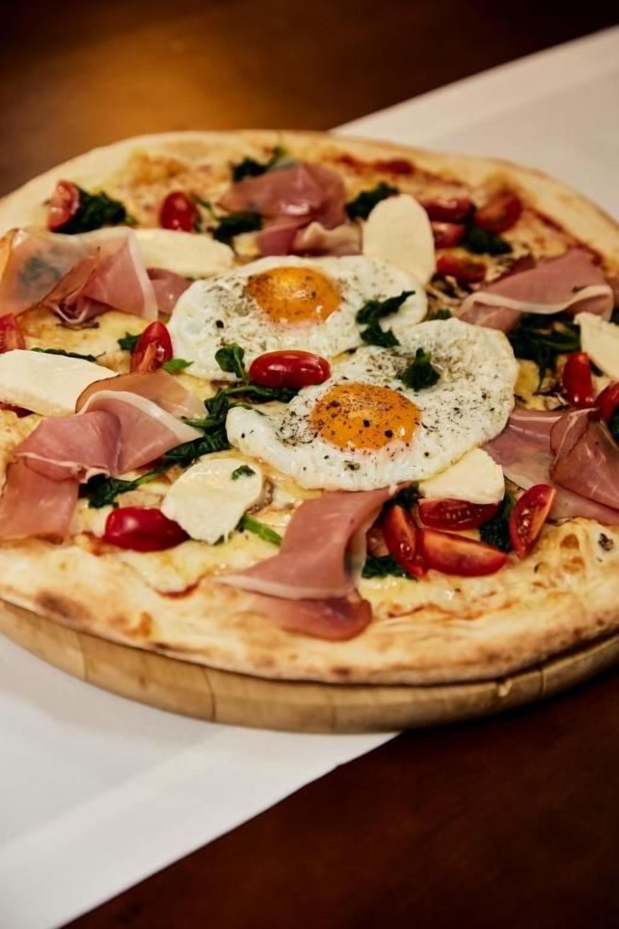 Pizza com diversos ingredientes sobre uma tábua de madeira.