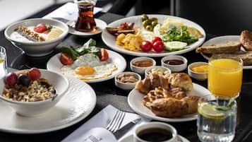 Mesa de café da manhã com diversos pratos, incluindo ovos, torradas e frutas.