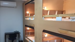 Quarto com beliches, mesa de estudo e ar condicionado.