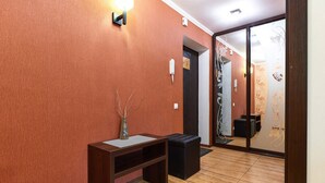 Uma área de recepção com um banco de madeira, um vaso e um telefone fixado na parede.