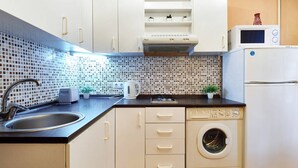 Uma cozinha compacta com pia, micro-ondas e máquina de lavar embutida.