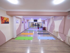 Quarto espaçoso com piso de madeira, um espelho grande e colchonetes de ginástica.