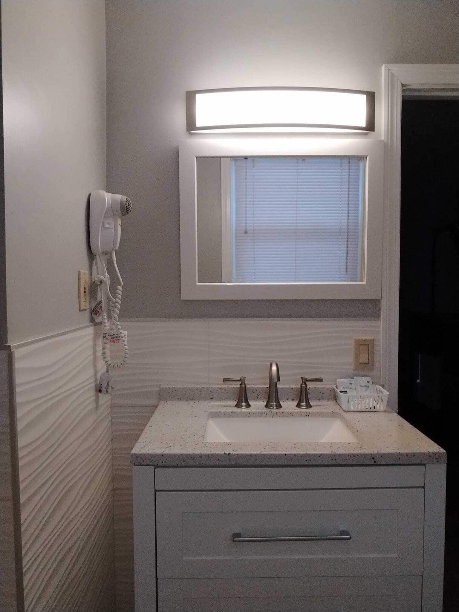 Casa de banho com lavatório, toucador e secador de cabelo fixado na parede.