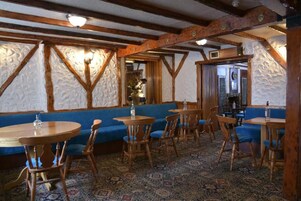 Um interior acolhedor com vigas de madeira, um tapete estampado e um banco estofado azul.