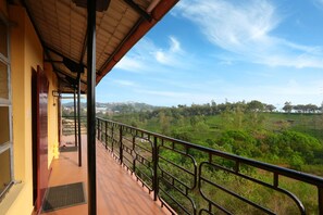 Varanda com guarda-corrimão de metal e vista para uma paisagem verde.