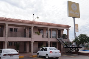 Hotel com placa indicando 'El Dorado Inn' e estacionamento com dois carros.