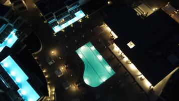 Vista aérea de um hotel com piscina, espreguiçadeiras e uma área coberta com assentos.