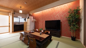 Uma sala de jantar tradicional japonesa com tatames, uma mesa baixa e uma televisão.