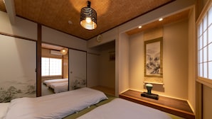 Um quarto tradicional em estilo japonês, com duas camas, teto de madeira e um quadro na parede.