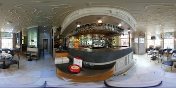 Uma área de bar com balcão curvo, diversas torneiras de cerveja e um espaço de estar com mesas e cadeiras.