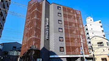 Um edifício moderno de hotel com fachada vertical, várias janelas e uma placa de destaque com a inscrição