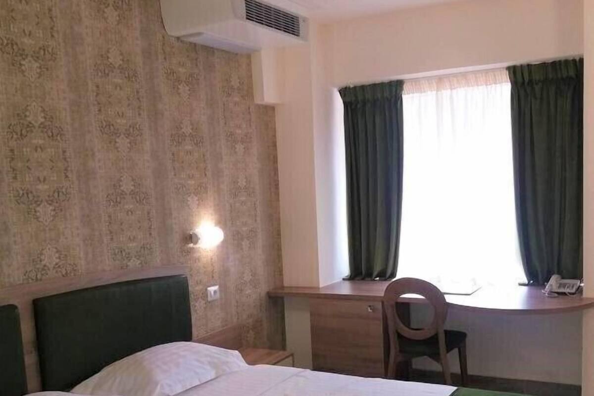 Quarto de hotel com cama, escrivaninha e cadeira.