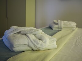 Cama bem arrumada com toalhas brancas dobradas.