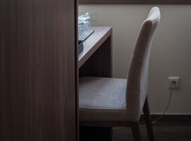 Uma cadeira com encosto alto e uma mesa de madeira com um recipiente de vidro e um objeto embrulhado.