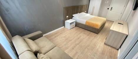 Quarto de hotel moderno com uma cama grande, um sofá, uma escrivaninha e um guarda-roupa.