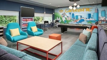 Uma área de convívio moderna com assentos, mesa de bilhar e um mural de Charlotte.