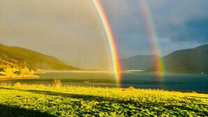 Paisagem com um lago, montanhas e um arco-íris.