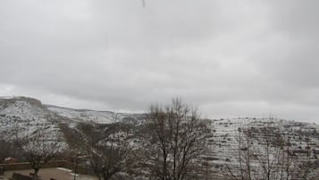 Um parque com bancos e um caminho, rodeado por colinas cobertas de neve.