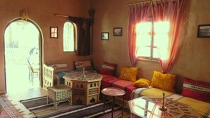 Quarto aconchegante com cama, uma mesa pequena, uma cadeira e uma janela com cortinas.