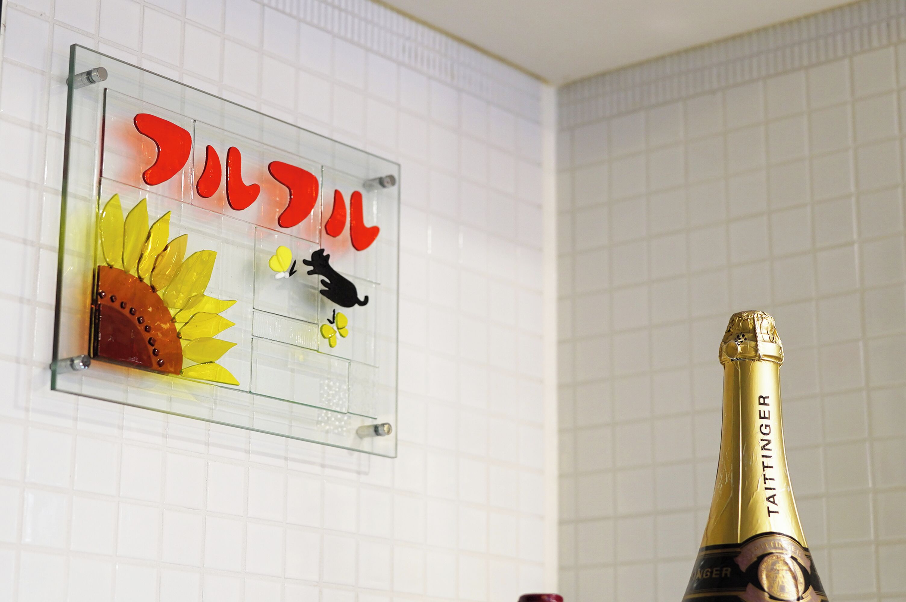 Uma garrafa de champanhe Taittinger e um letreiro decorativo com caracteres japoneses.
