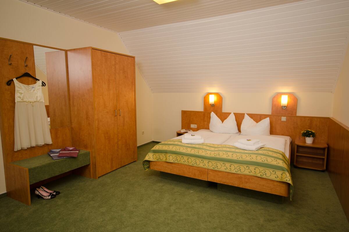 Quarto de hotel com cama, um banco, um guarda-roupa e um espelho.