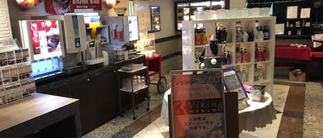 Um saguão de hotel com um bar de bebidas Coca-Cola, uma exposição de produtos de higiene pessoal e um aviso para sais de banho Viking.