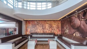 Um hall amplo com teto alto, um grande mural e uma área de estar moderna.