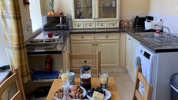 Uma cozinha com uma mesa de jantar posta para o café da manhã, incluindo croissants, scones e suco.