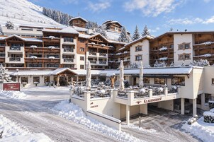 Um hotel coberto de neve, com várias varandas e uma área de recepção.
