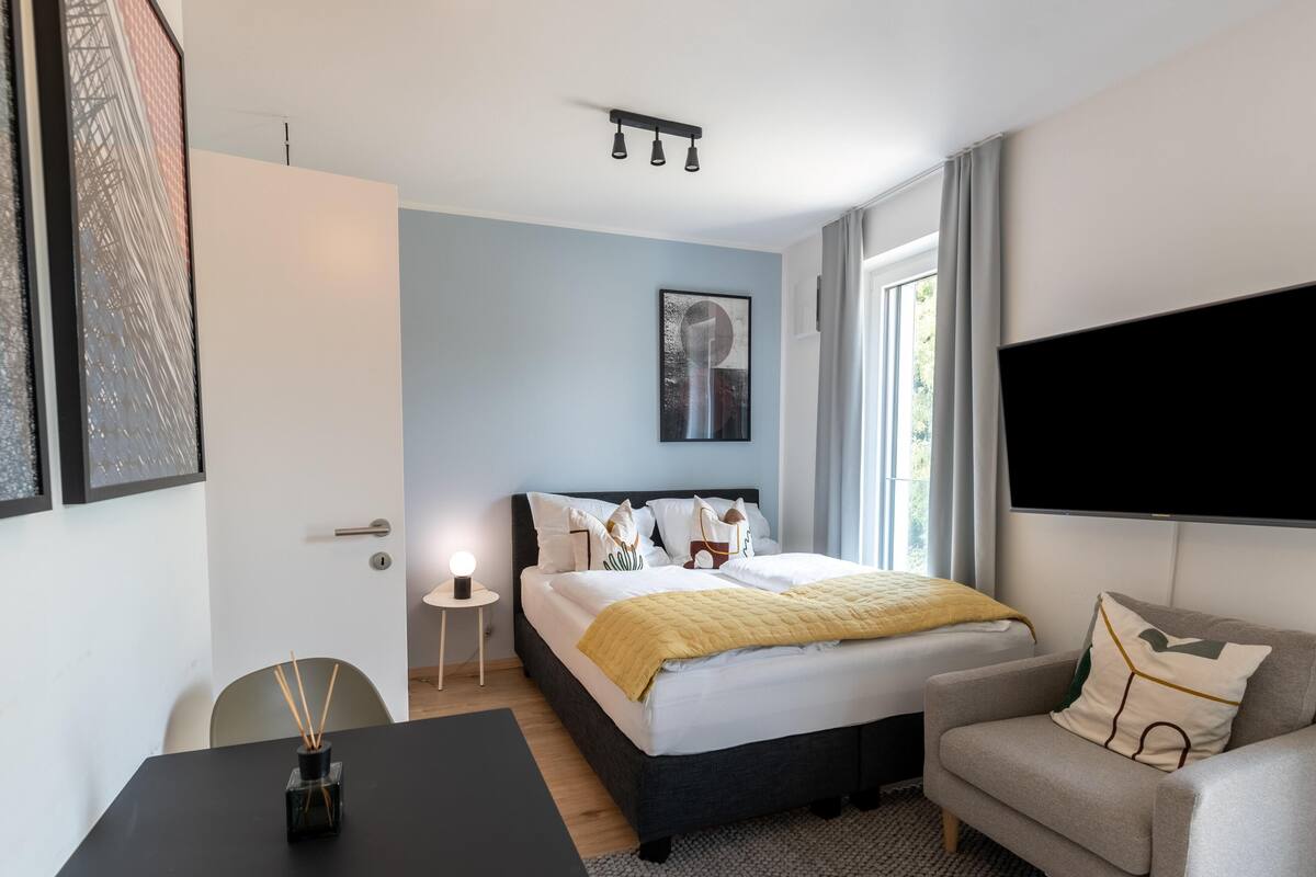 Quarto de hotel com cama, televisão, escrivaninha e cadeira.