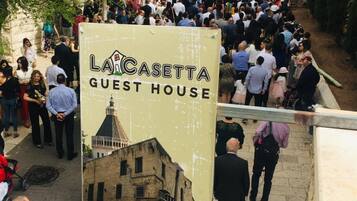 Área movimentada com uma placa indicando La Casetta Guest House, sinalizando um local para visitantes.