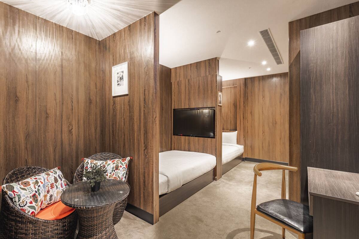 Quarto moderno com cama, TV, móveis de vime e painel de parede de madeira.