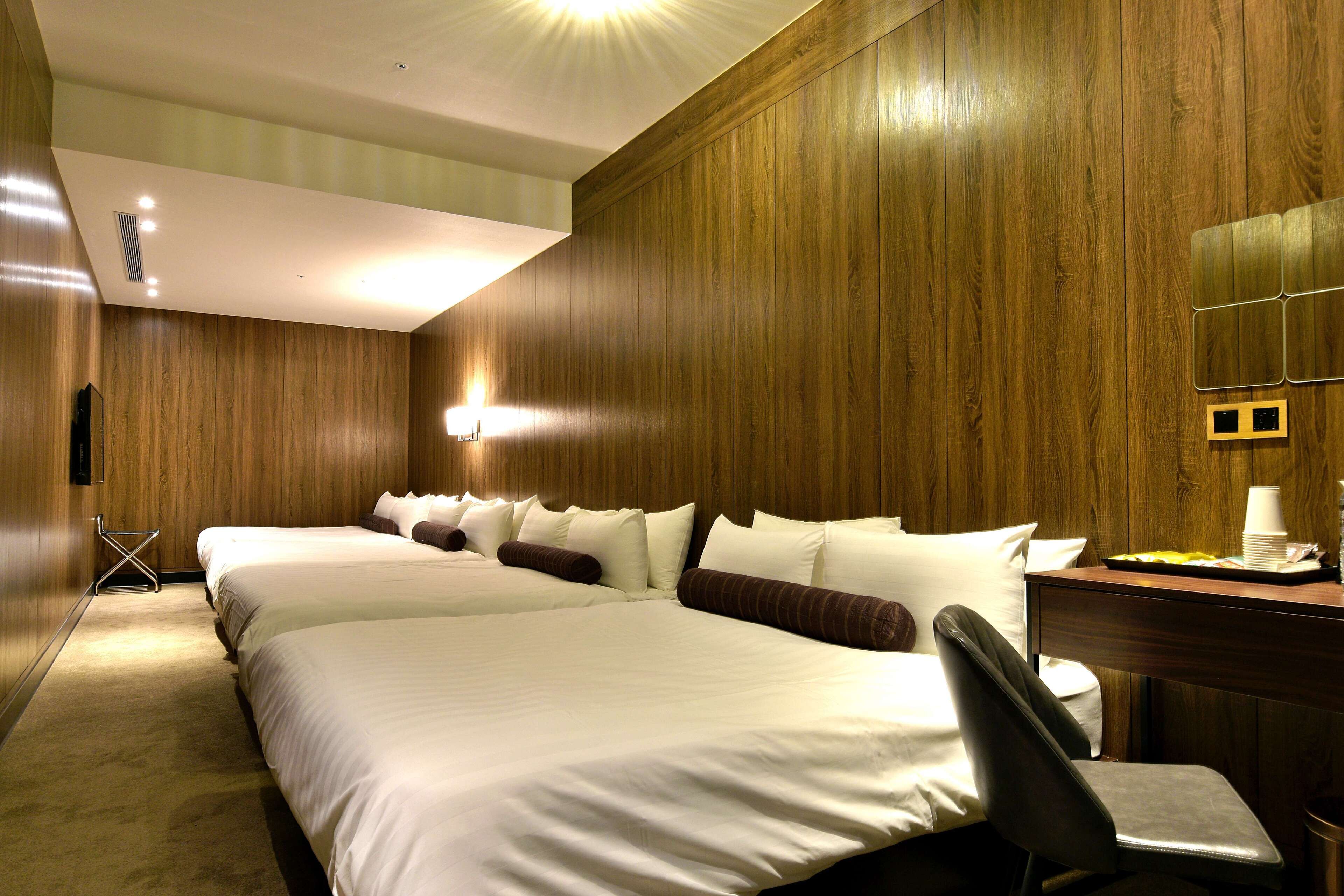 Quarto de hotel com duas camas grandes, uma escrivaninha com cadeira, uma mesa pequena com bandeja de itens de café da manhã e um espelho na parede.