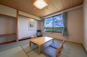 Um quarto japonês tradicional com tatames, uma mesa de madeira baixa e vista para o exterior através de uma grande janela.