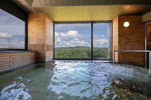Uma área de hidromassagem com vista para uma paisagem montanhosa através de grandes portas deslizantes.