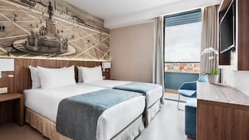 Quarto de hotel com uma cama grande, uma escrivaninha, uma cadeira e um mural com vista para a cidade.