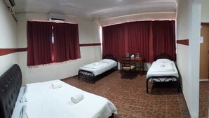 Quarto de hotel com duas camas de solteiro, uma escrivaninha e uma cadeira.