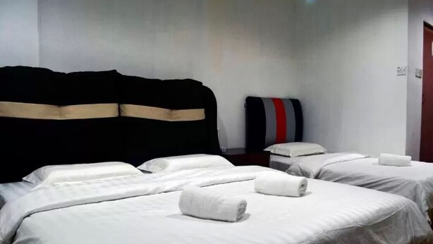 Quarto de hotel com duas camas, cada uma com roupa de cama e toalhas brancas impecavelmente arrumadas.