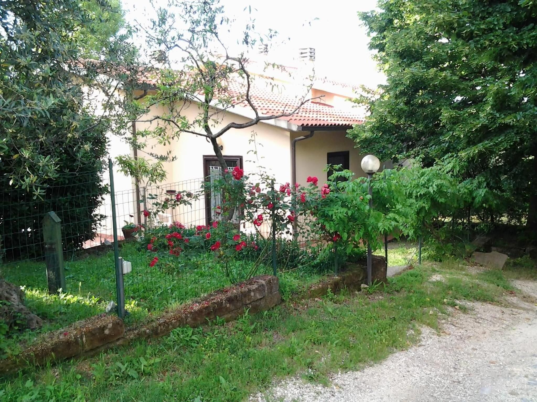 Uma casa com jardim, caminho de pedras e cerca.