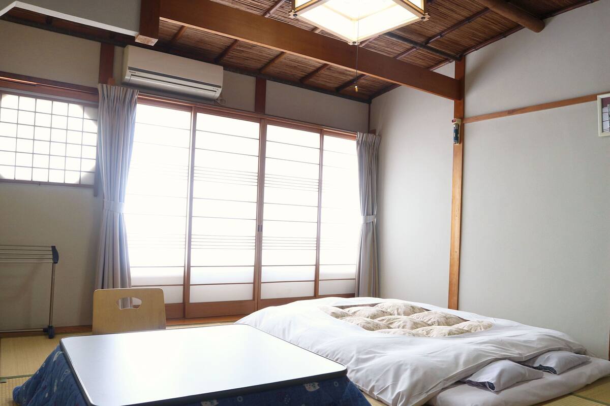Quarto tradicional japonês com tatames, futon, escrivaninha e porta de papel shoji.