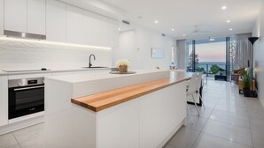 Uma cozinha moderna com armários brancos, bancada de madeira e forno embutido.