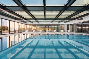 Piscina interior moderna com tetos de vidro e espreguiçadeiras.