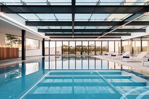 Piscina interna com tetro de vidro transparente e espreguiçadeiras.