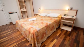Quarto bem arrumado com cama, mesas de cabeceira e guarda-roupa.