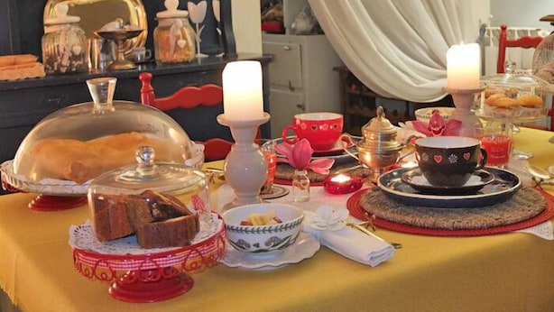 Uma mesa posta para refeição com diversos pratos, um bule de chá e uma vela.