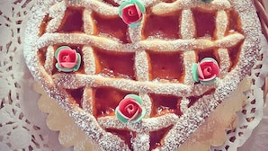 Um waffle em formato de coração com açúcar em pó e rosas decorativas sobre um jogo de tabuleiro.